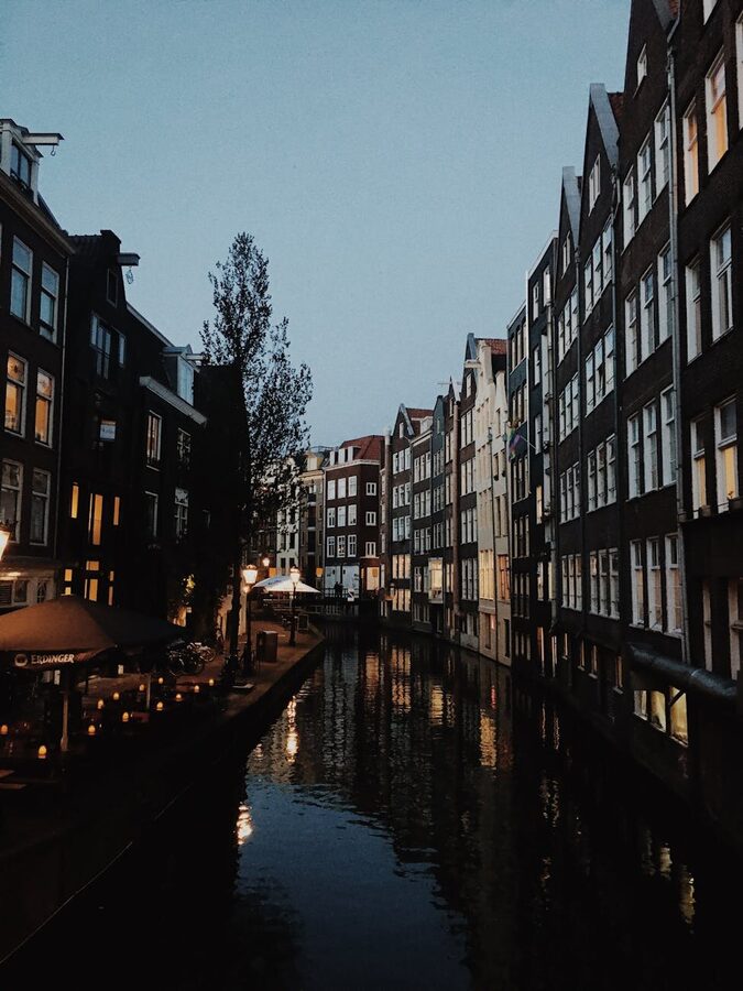 Evening scene of a canal in Amsterdam with lights reflecting on water