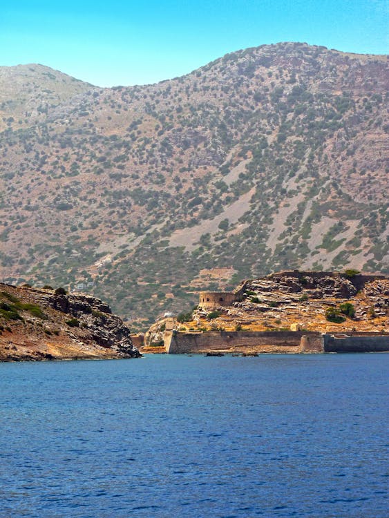 A picturesque view of Spinalonga Island with mountains and sea in Greece.