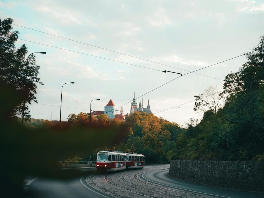 Vintage tram travels through Prague streets with Prague Castle visible in the background