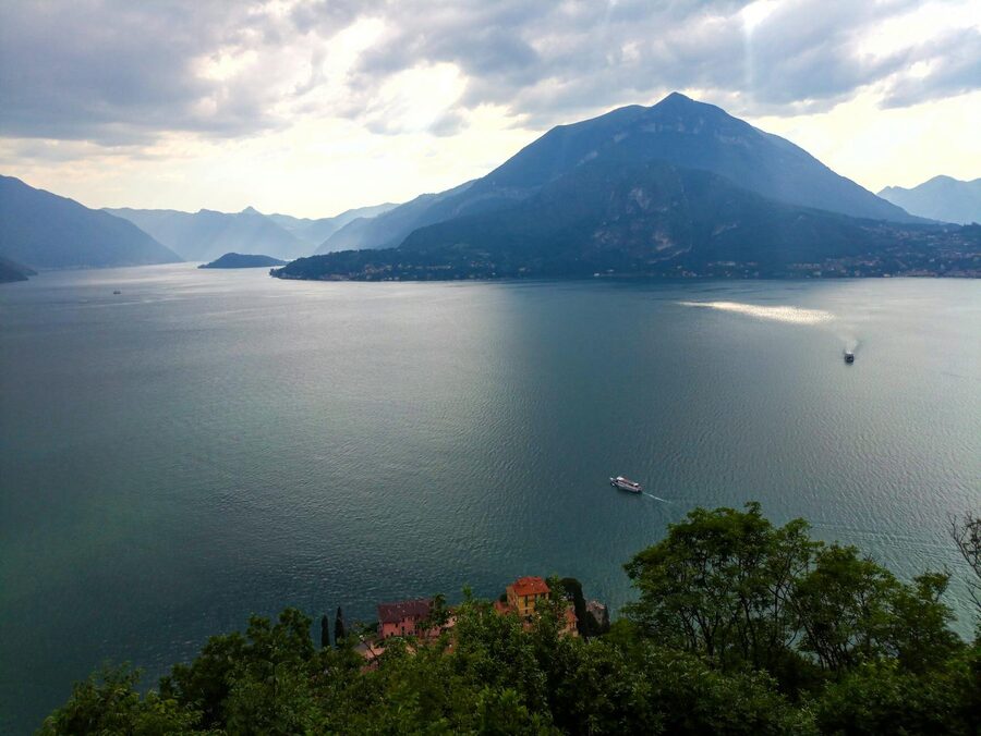 A boat on Lake Como at sunrise with a mountain village in the background