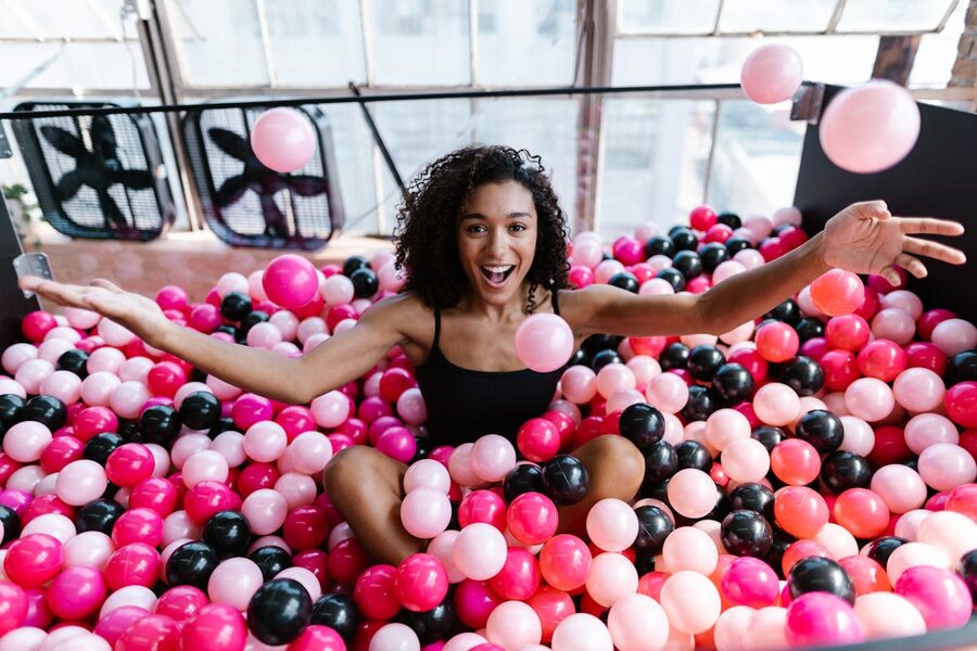 Excited woman having fun in a colorful ball pit indoors