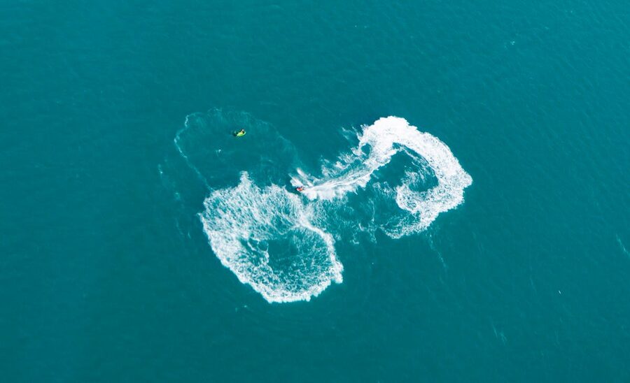 Aerial view of a jet ski creating water trails on blue ocean