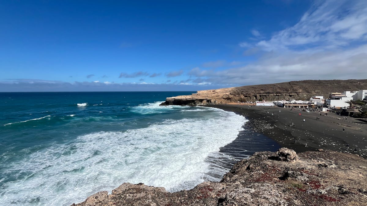 Waves crashing on Ajuy Beach Fuerteventura against dramatic volcanic cliffs