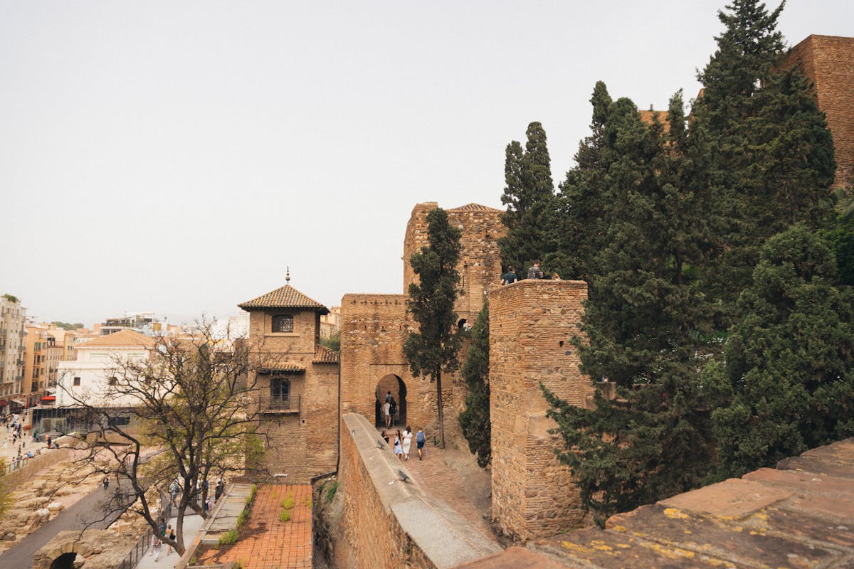 View of Alcazaba fortress stone walls and rooftops surrounded by greenery in Malaga