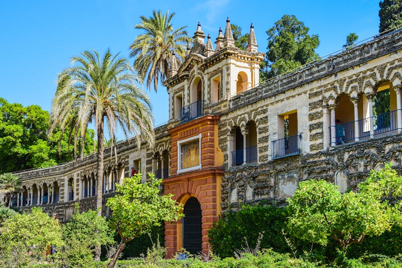 Panoramic view of the Alcazar Palace with lush gardens and palm trees