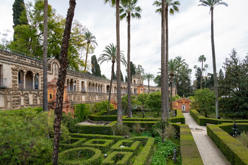 Lush royal gardens of the Alcazar in Seville with architecture and greenery