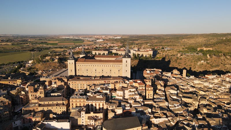 The imposing Alcazar fortress of Toledo illuminated by warm sunset light against a colorful sky