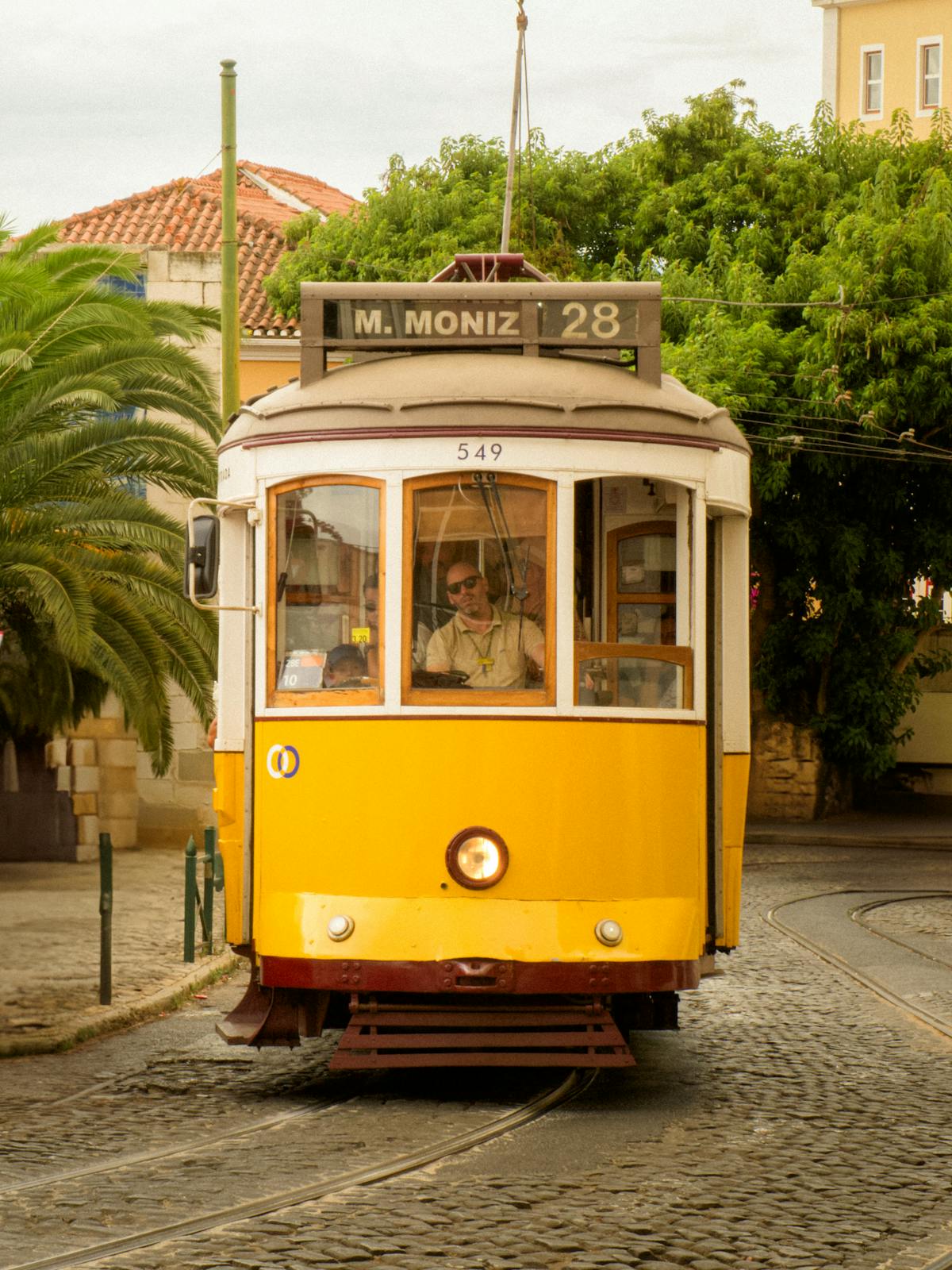 Tram rolling through Alfama cobblestone streets past traditional Portuguese buildings