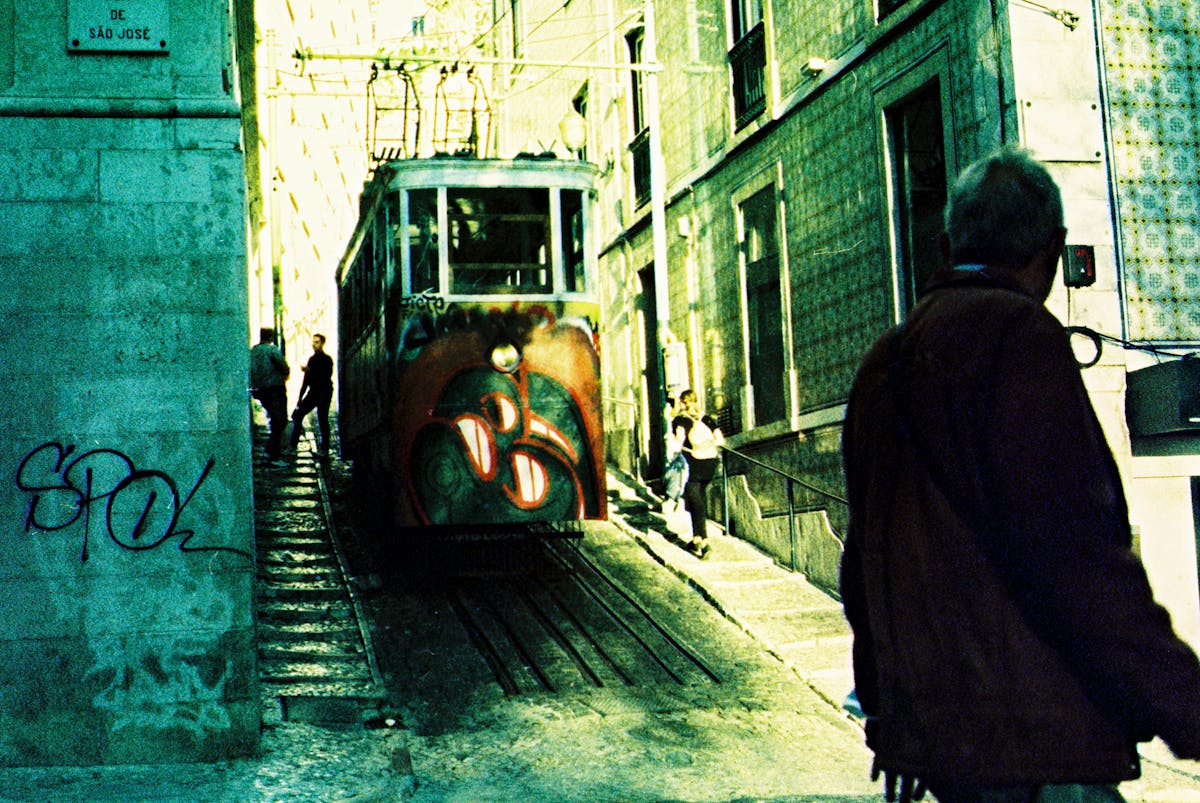 Tram squeezing through a narrow Lisbon street lined with old buildings