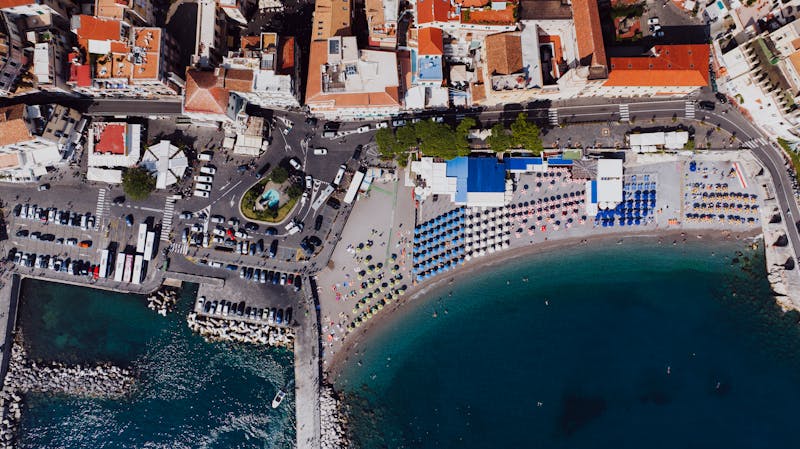 Aerial view of Amalfi beach with colorful umbrellas and the historic town rising behind it