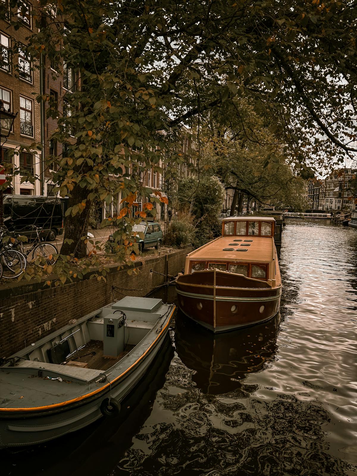 Amsterdam canal with boats and autumn foliage along the tree-lined banks