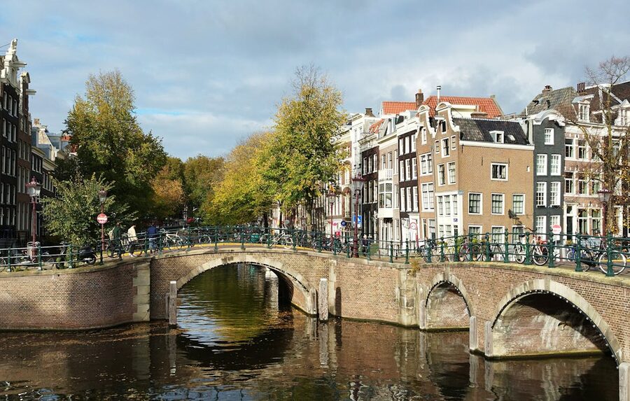 Amsterdam canal bridge with autumn foliage and historic buildings
