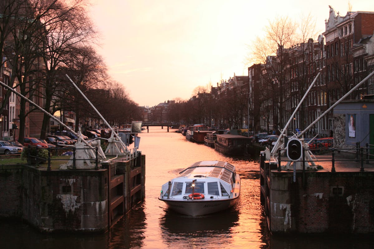 A canal boat navigating through Amsterdam canals at sunset