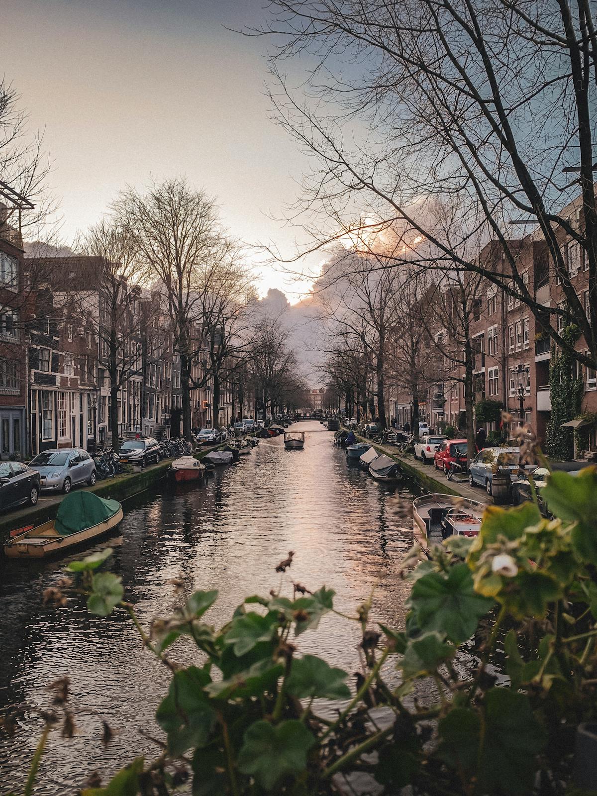 Amsterdam canal with boats and historic buildings during a warm sunset