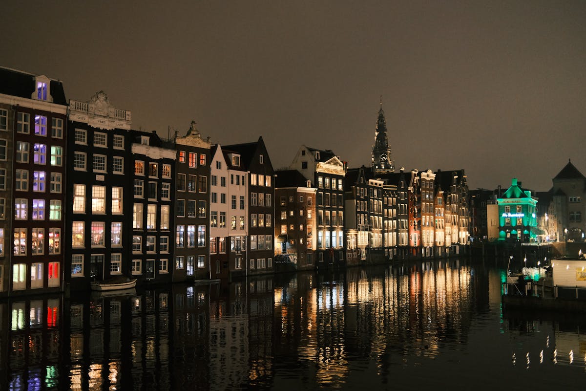 Amsterdam canal houses reflecting on water at evening