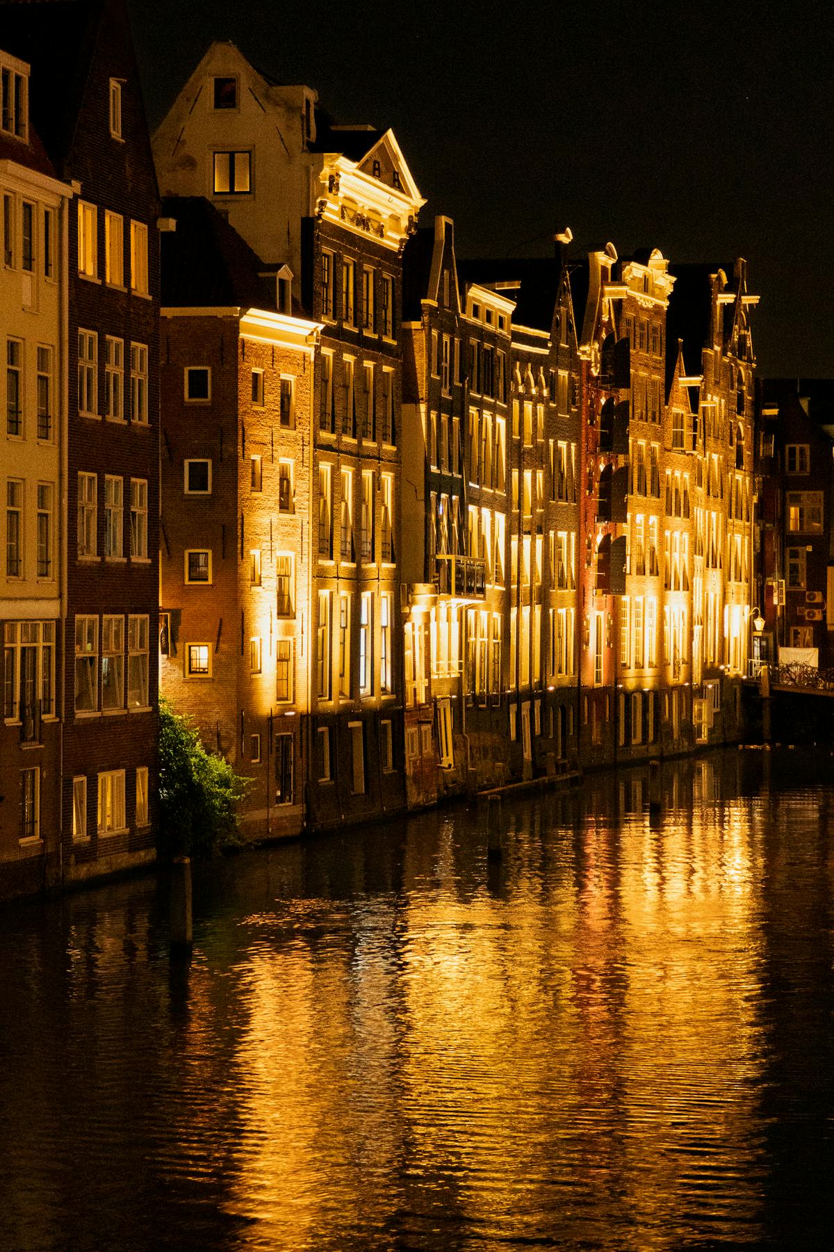 Amsterdam canal houses illuminated at night along a quiet waterway