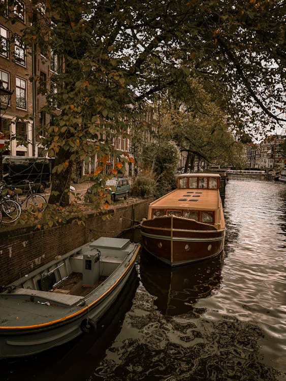 Amsterdam canal with boats moored alongside historic buildings in autumn