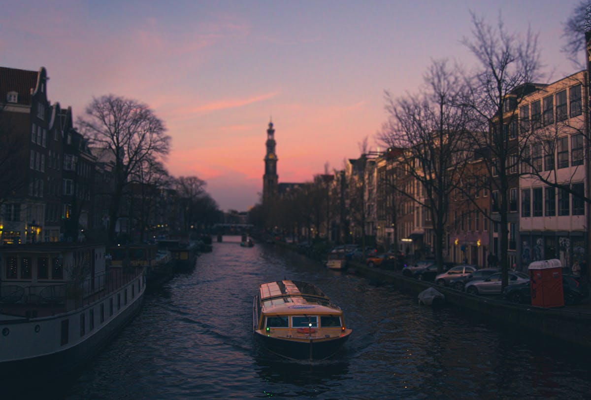 Scenic view of Amsterdam canal at sunset with boat and historic architecture