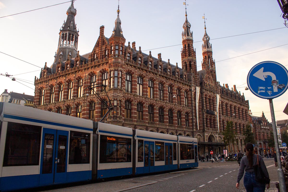 Historic building in Amsterdam with a tram passing by at sunset