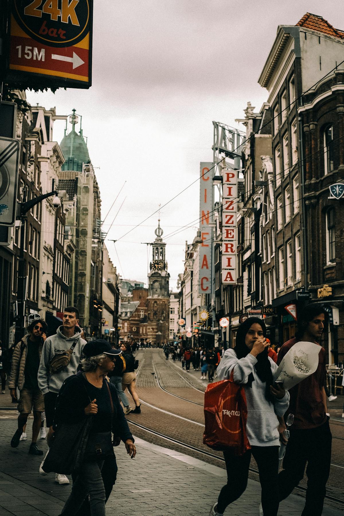 Crowded Amsterdam shopping street with pedestrians walking past historic buildings