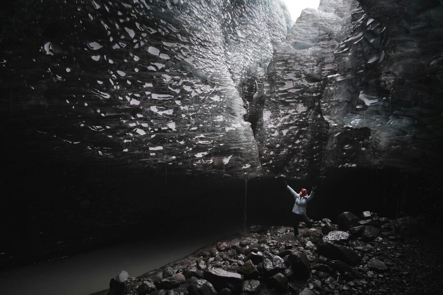 An adventurous hiker explores the grandeur of an ice cave in Iceland, showcasing nature's rugged bea