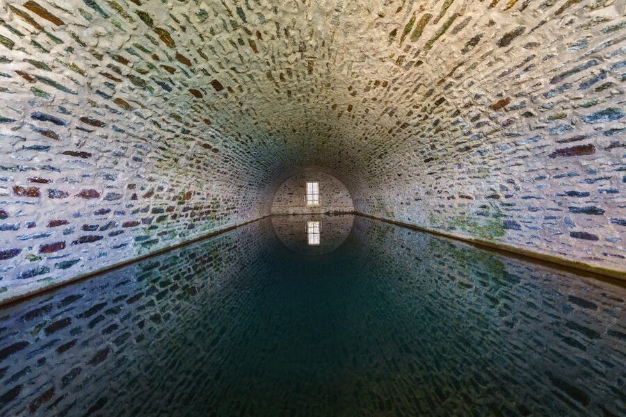 Symmetrical view of a stone tunnel with water reflection on the ground