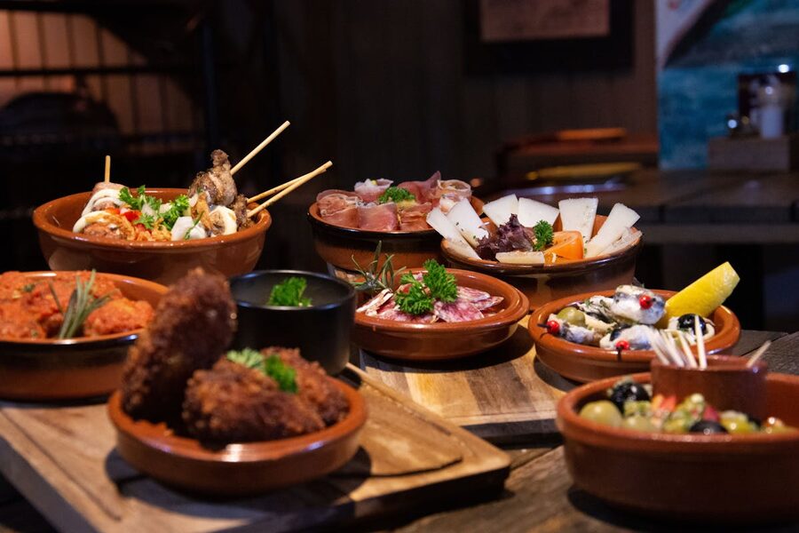 Inviting spread of various tapas dishes arranged on wooden boards in a cozy restaurant