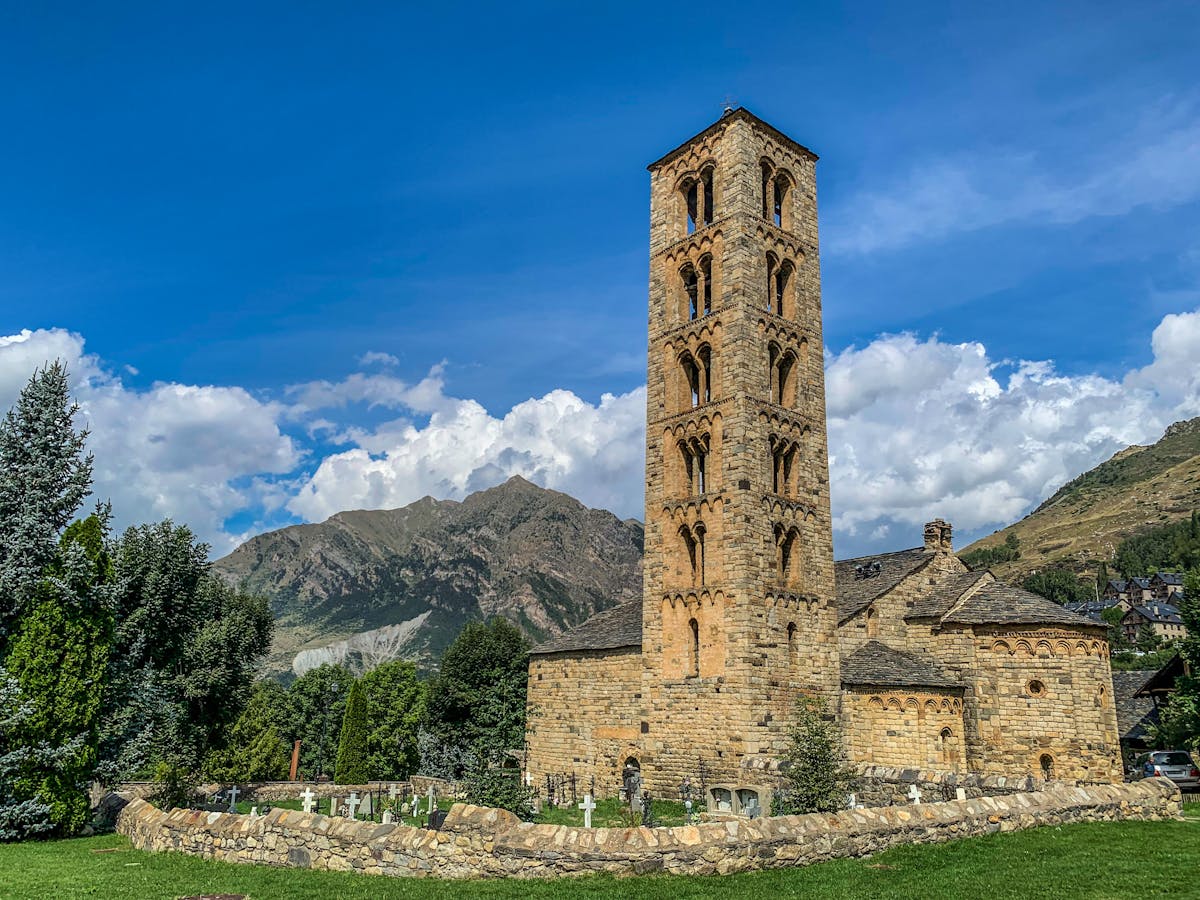 Rustic stone church with bell tower set against scenic Andorran mountain backdrop