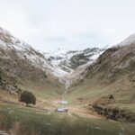 Green valley in Andorra surrounded by snow-capped Pyrenees mountains