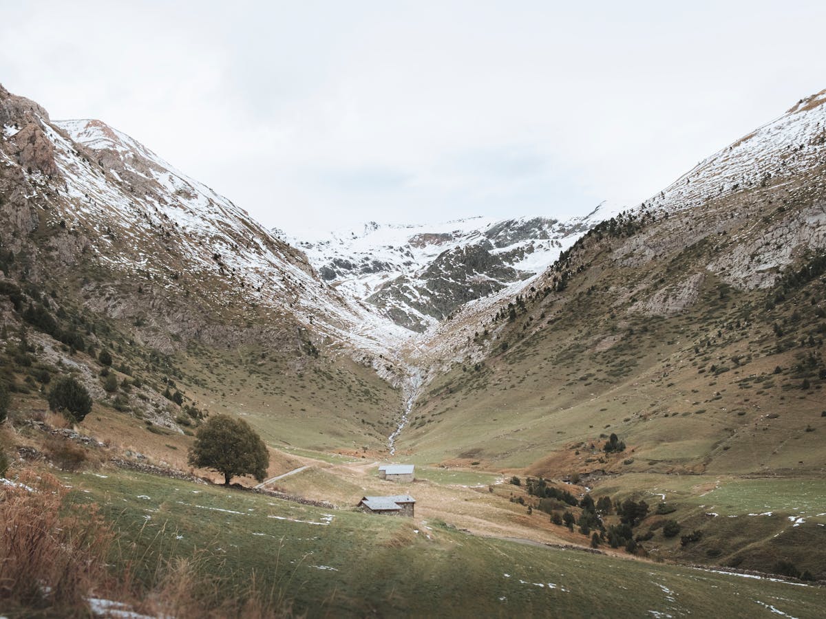 Green valley in Andorra surrounded by snow-capped Pyrenees mountains