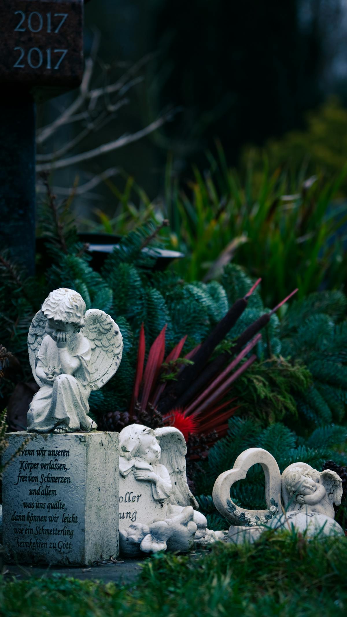 Cemetery scene with angel statues and a heart-shaped stone memorial surrounded by greenery