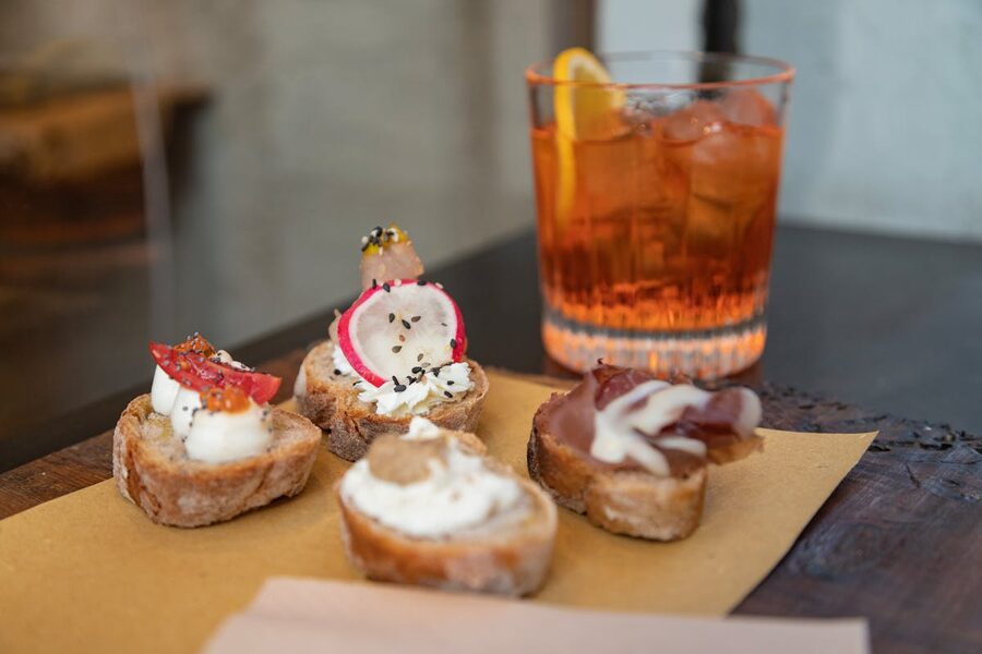 Crostini appetizers alongside an Aperol Spritz cocktail on a table