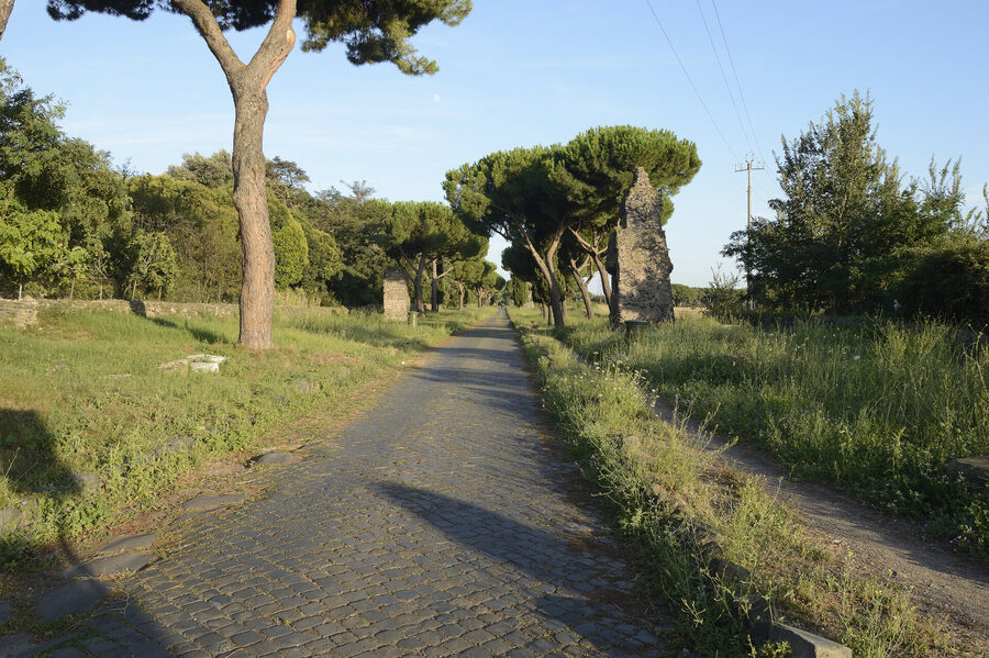 The ancient Appian Way near Rome with original Roman paving stones and tomb ruins along the roadside
