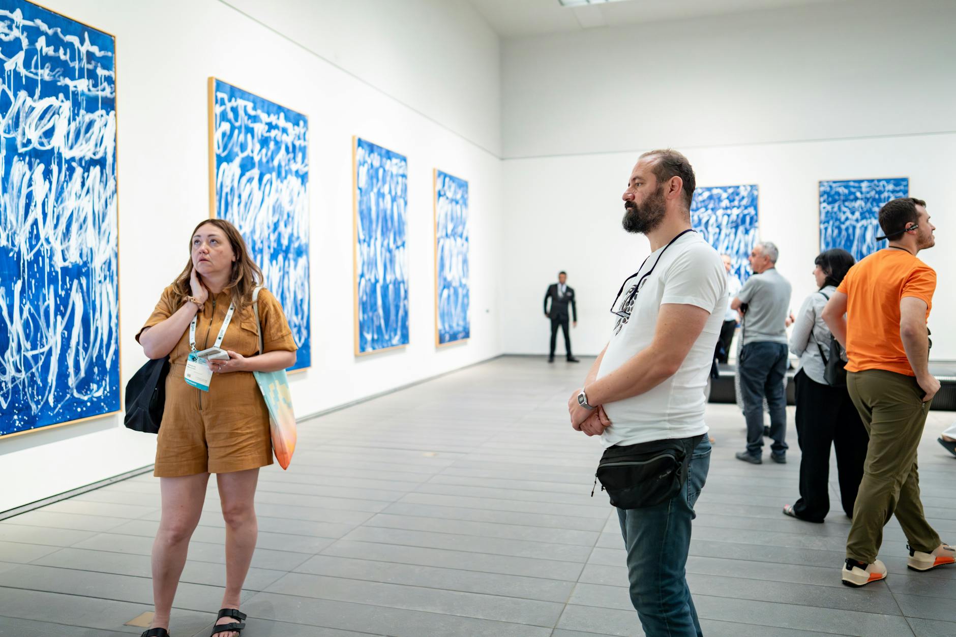 Visitors in an art gallery engaging with blue abstract artworks