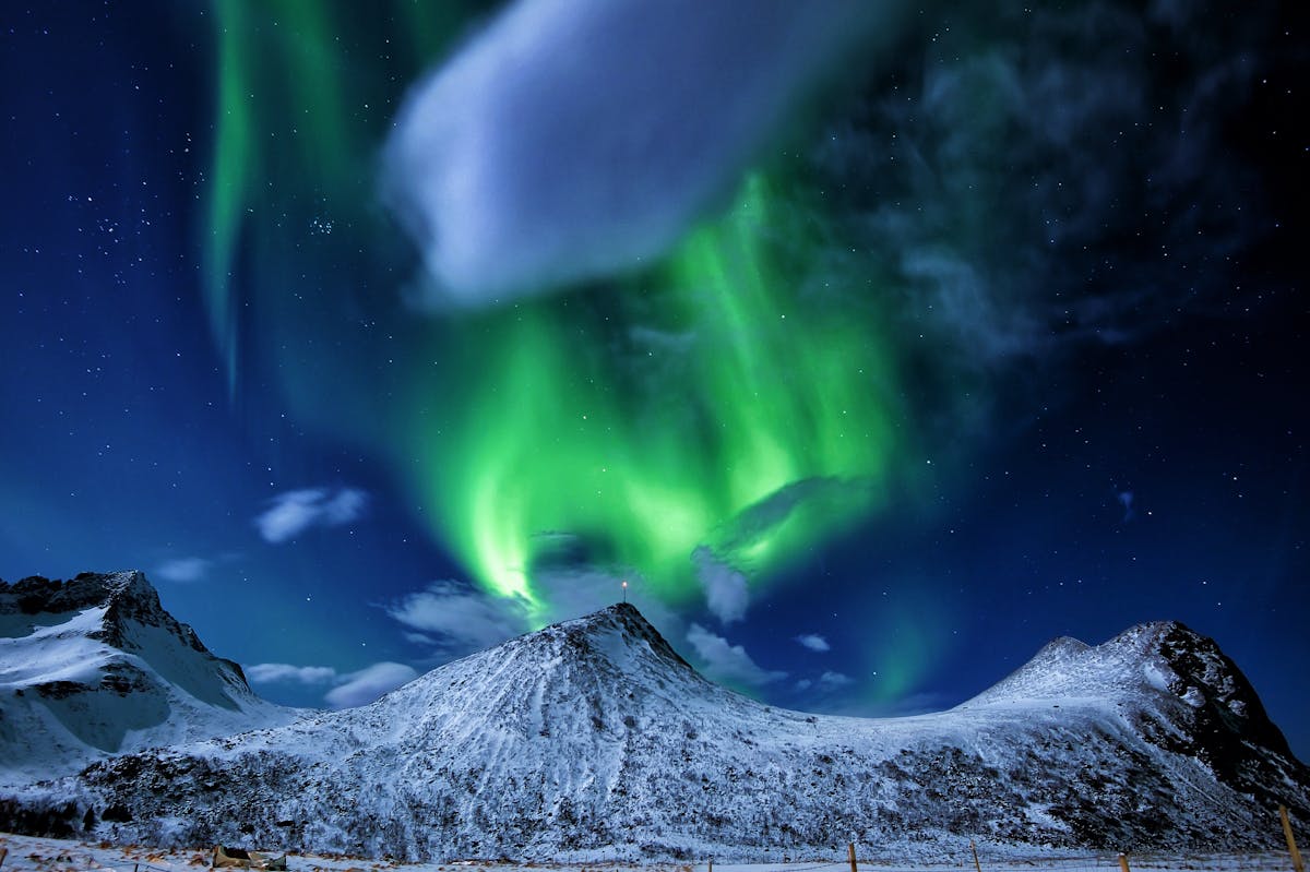 Aurora borealis lights up the sky over snowy peaks in Norway