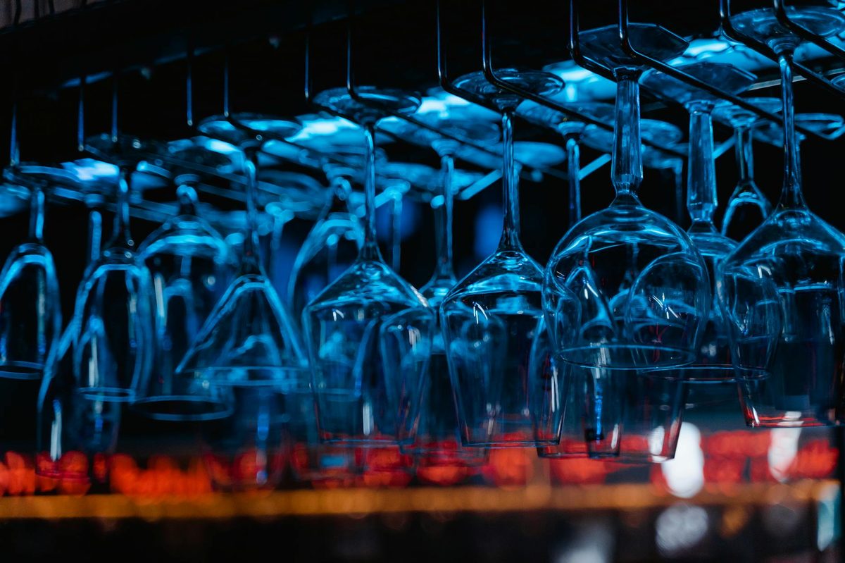 Glassware hanging inside a bar illuminated with blue light