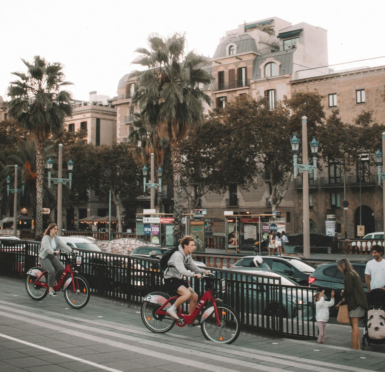 People cycling through Barcelona streets with palm trees and urban scenery