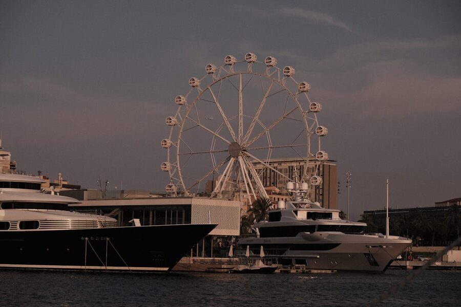 Barcelona ferris wheel and yachts at sunset in the harbor