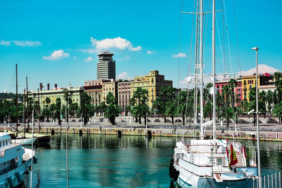 Barcelona harbor with boats and colorful buildings under blue sky