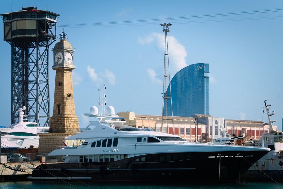 Marina with yachts in Barcelona harbor with city buildings in background