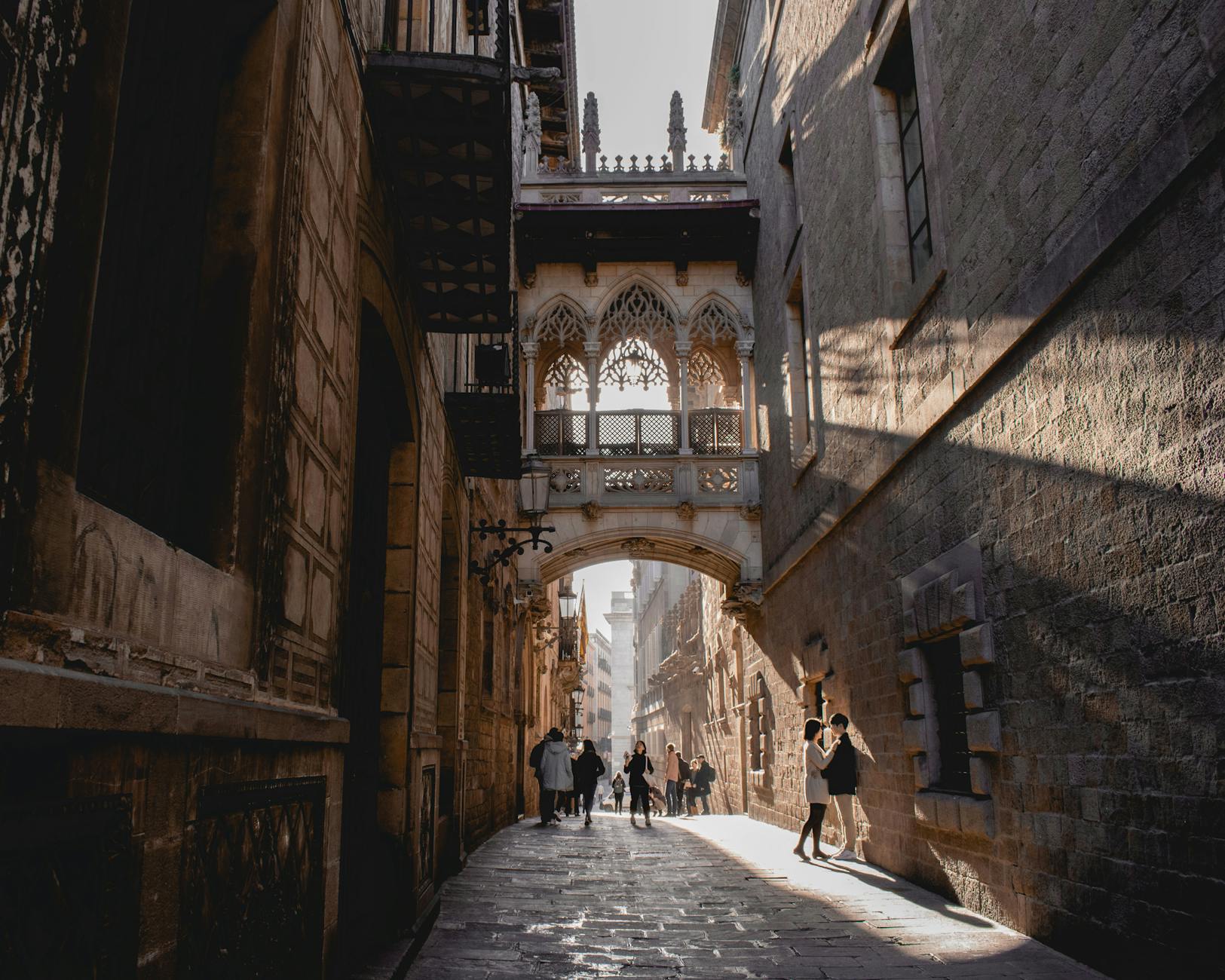 People walking under Pont del Bisbe in Barcelona Gothic Quarter