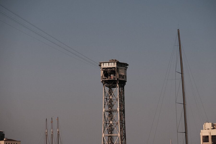 View of Port Cable Tower with sailboat mast in Barcelona during sunset