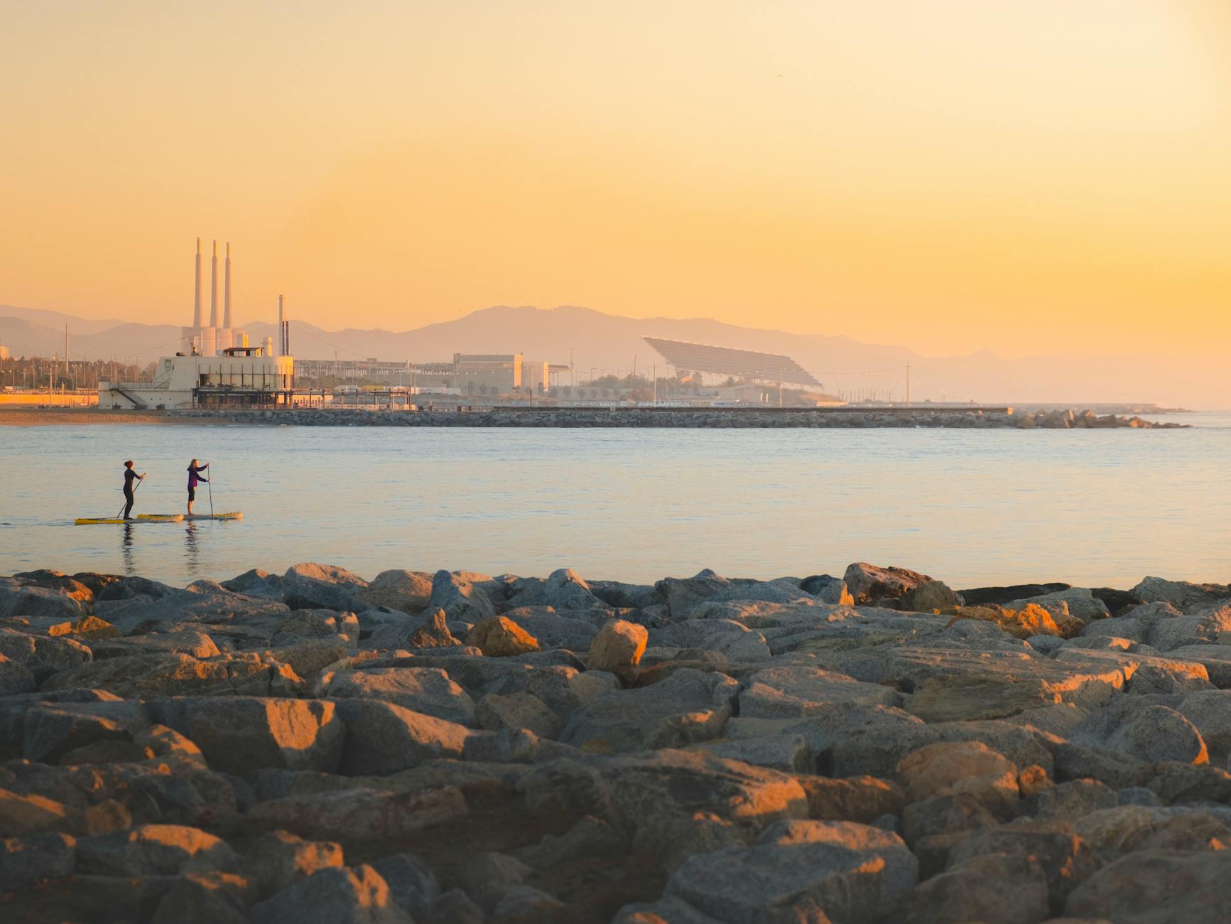Barcelona's waterfront glowing during golden hour with palm trees and buildings