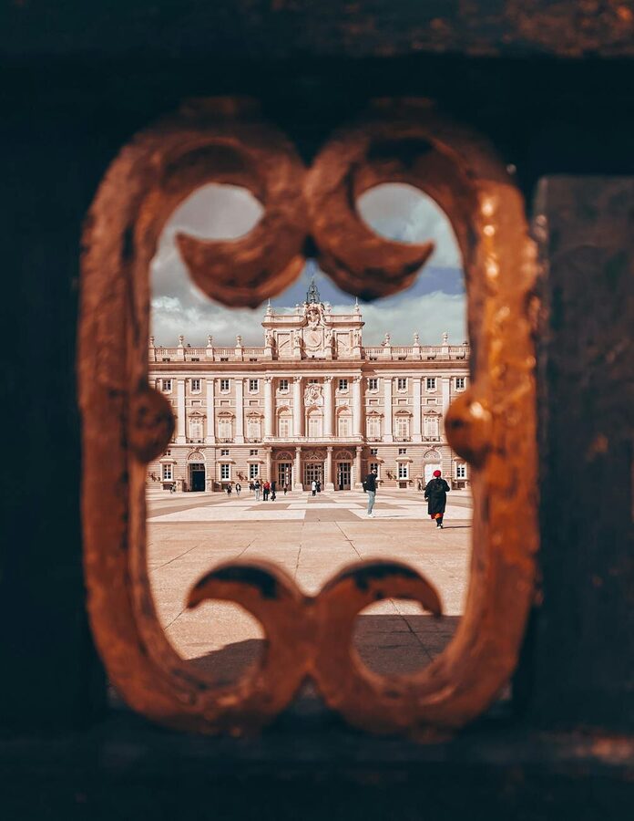 The Royal Palace of Madrid on a cloudy day with visitors in the courtyard