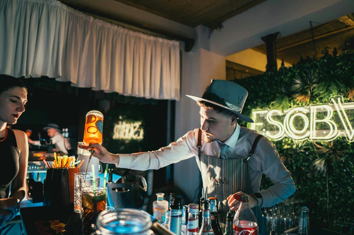 Bartender mixing a cocktail in a neon-lit bar