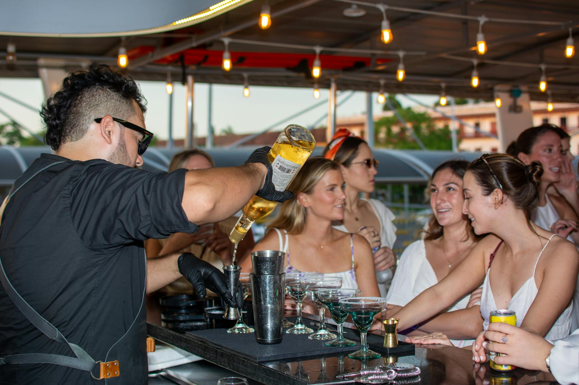 Bartender preparing cocktails at an outdoor bar counter during sunset