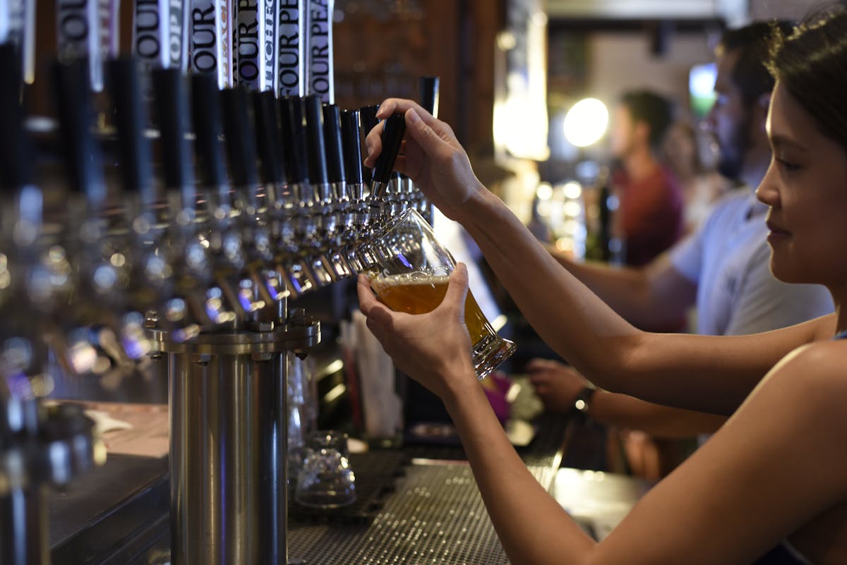 Female bartender pouring craft beer from a tap in a pub setting