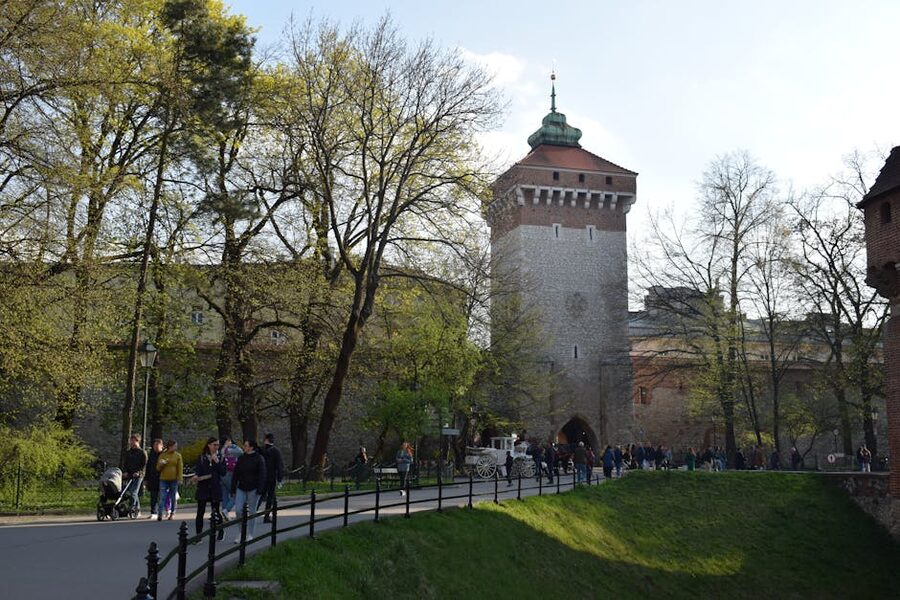 View of Kraków's city wall and tower with people strolling in spring