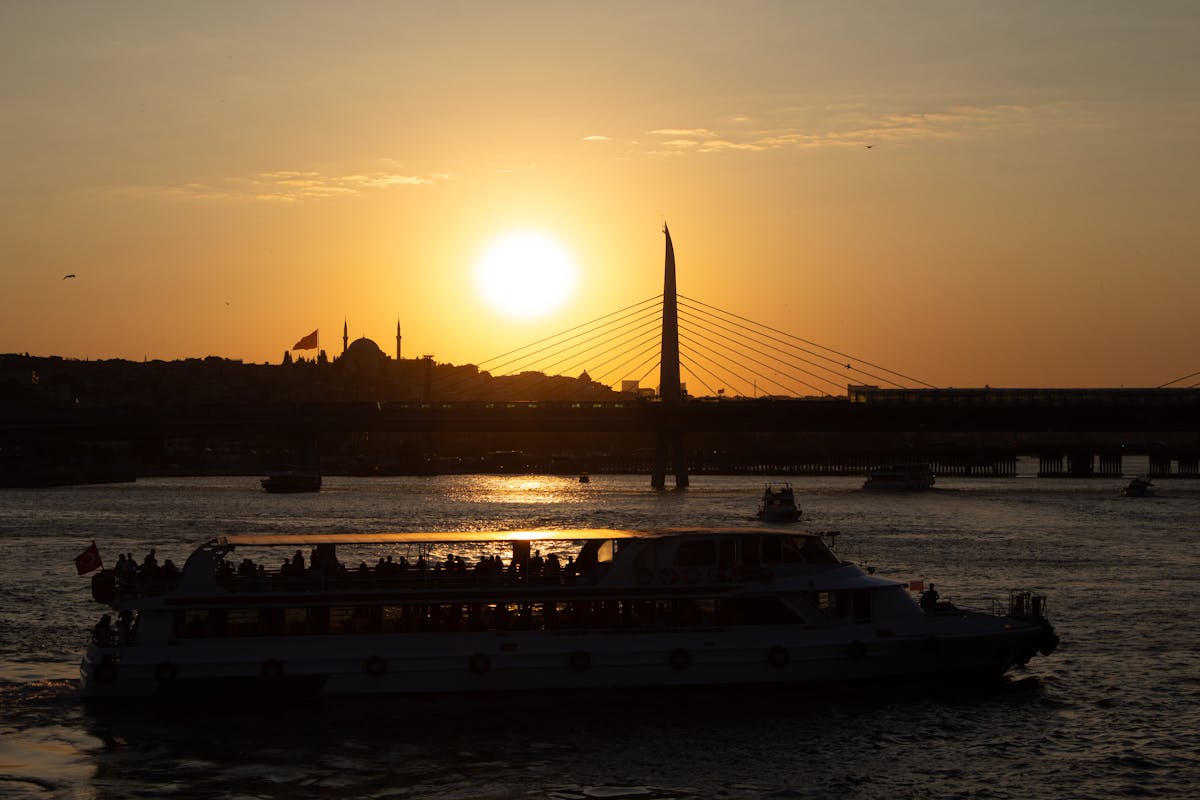 Scenic view of a boat on the Bosphorus at sunset with bridge silhouette