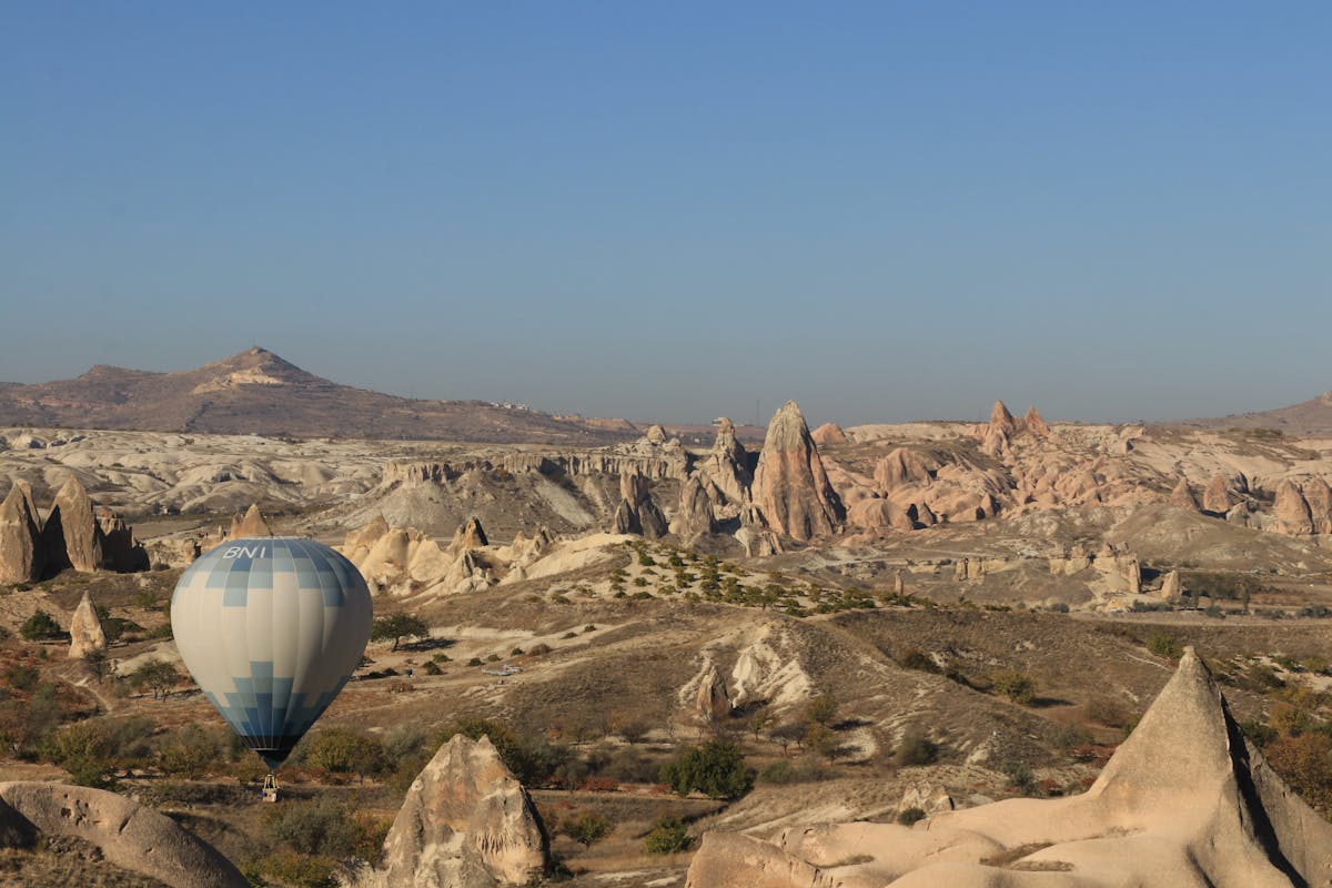 Single hot air balloon floating over Cappadocia rock formations in daylight